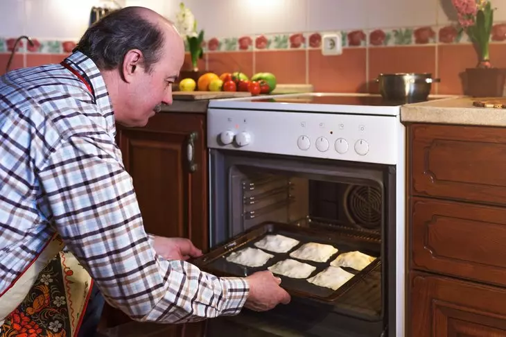 Omul scoate plăcintele din cuptor.