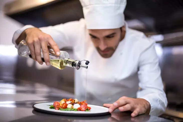 Chef adicionando óleo à comida