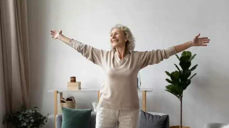 Senior feliz estirando sus brazos en casa