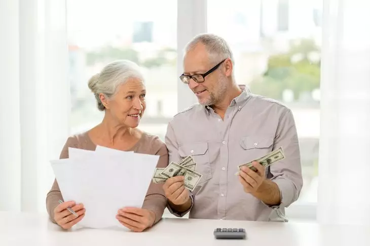 Personas mayores planificando felizmente el presupuesto y gastando dinero