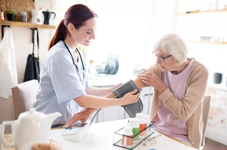 tuisgesondheidsverpleegster wat 'n senior se bloeddruk neem