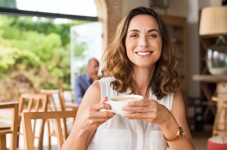 Hermosa muller sorrinte tomando café