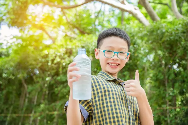 Un ragazzo tiene una bottiglia d'acqua