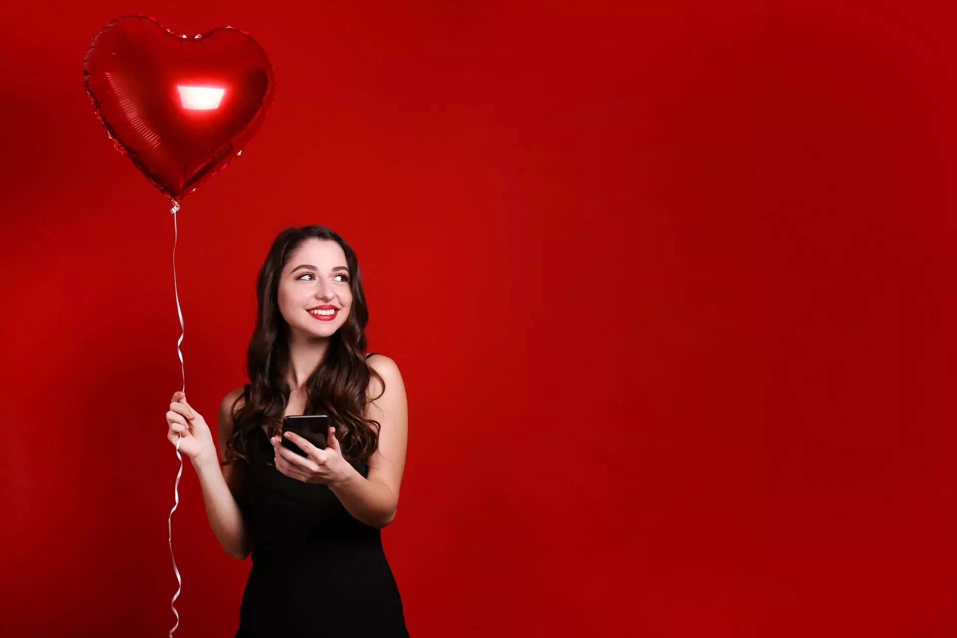 Femme avec un téléphone portable et un ballon coeur