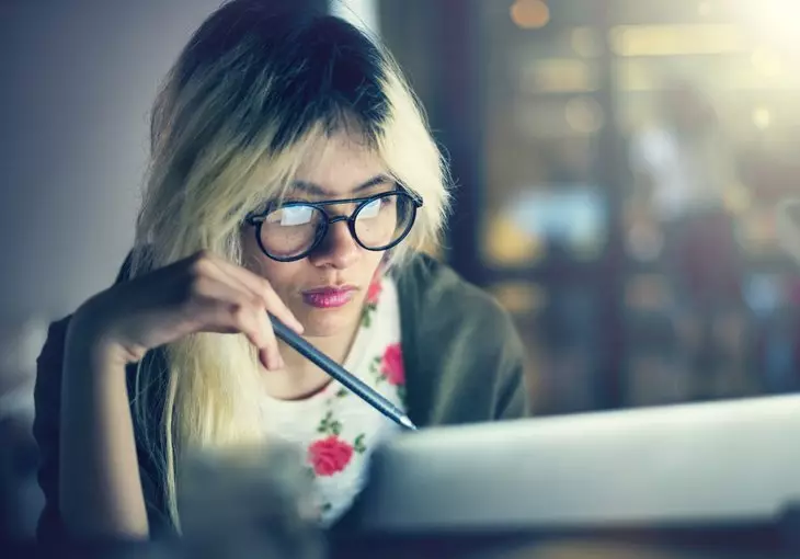 Een jonge vrouw leest aandachtig op haar laptop