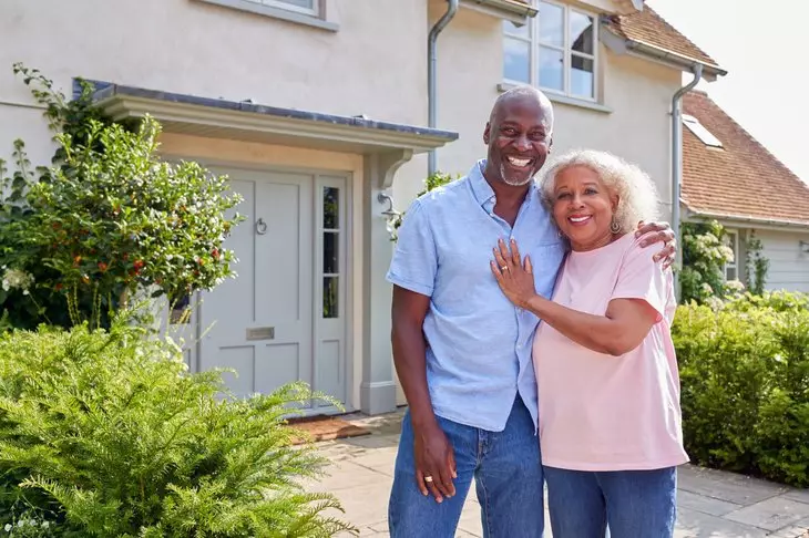 Lykkelig seniorpar foran huset deres