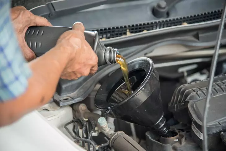 Homme changeant l'huile moteur dans sa voiture