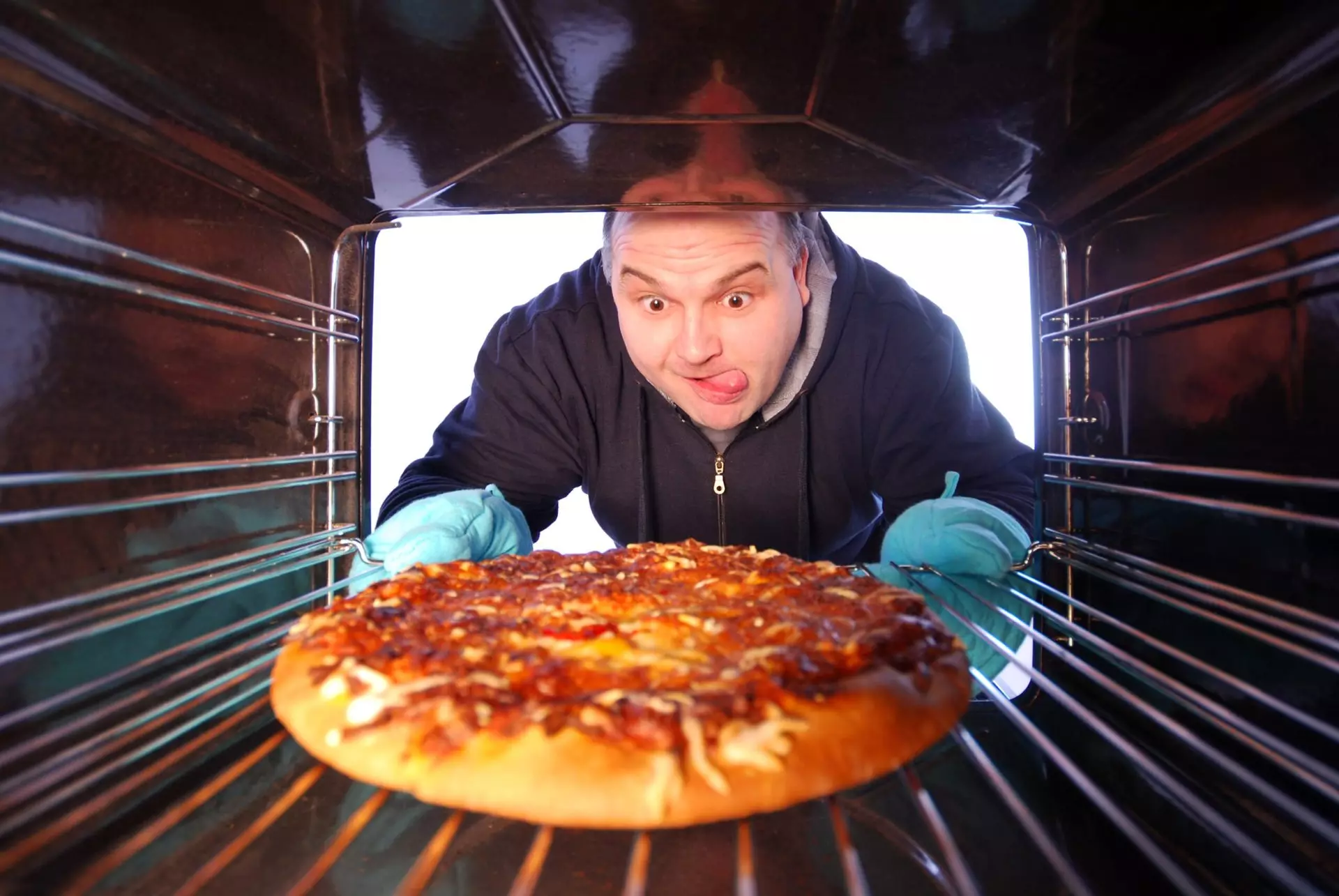 Mann zieht eine Tiefkühlpizza aus dem Ofen