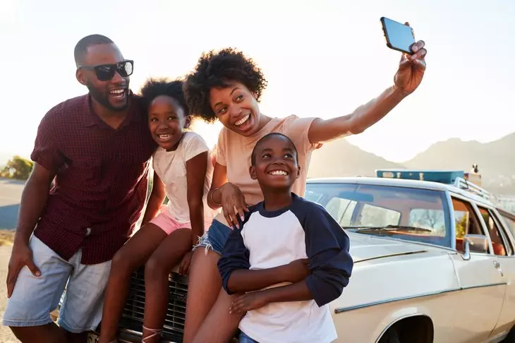 Familia afroamericana tomando selfie en auto.