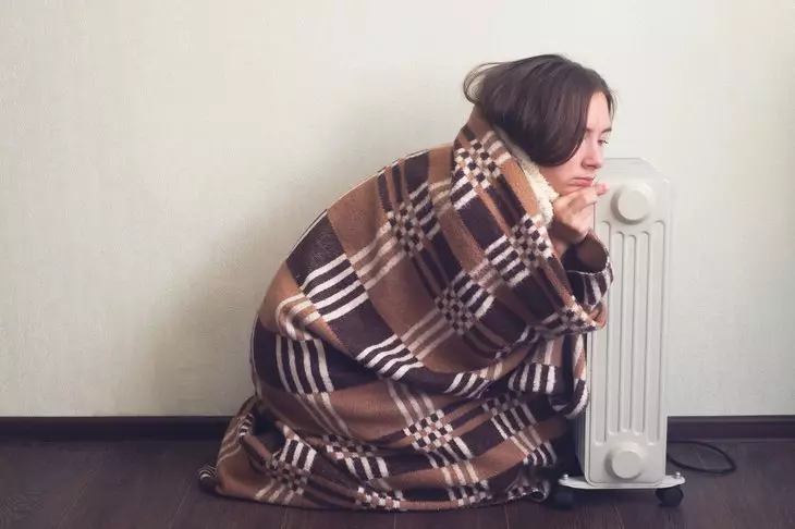 Jeune femme froide par radiateur électrique