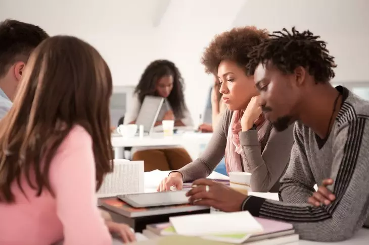 Studenten werken samen aan een tafel.