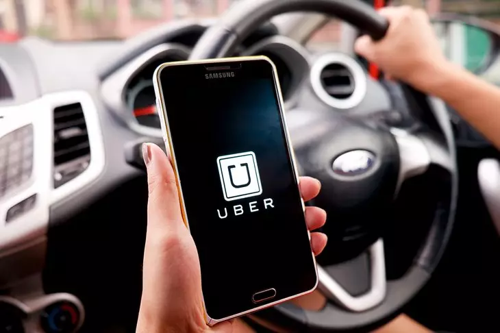 司機手持智能手機，屏幕上顯示 Uber 圖標