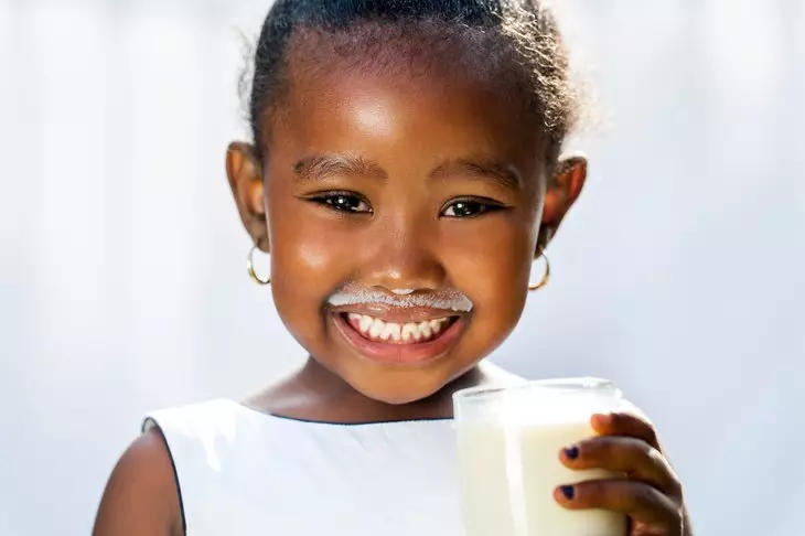 Bocah wadon cilik karo kumis susu, mesem.