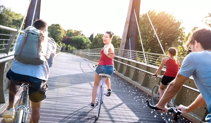 Estudantes universitarios andando en bicicleta nunha cidade