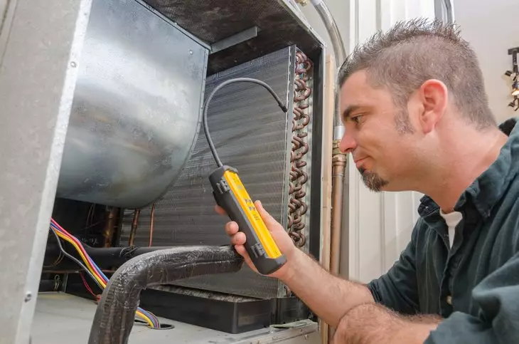 Reparador de HVAC trabajando en una unidad de aire acondicionado.