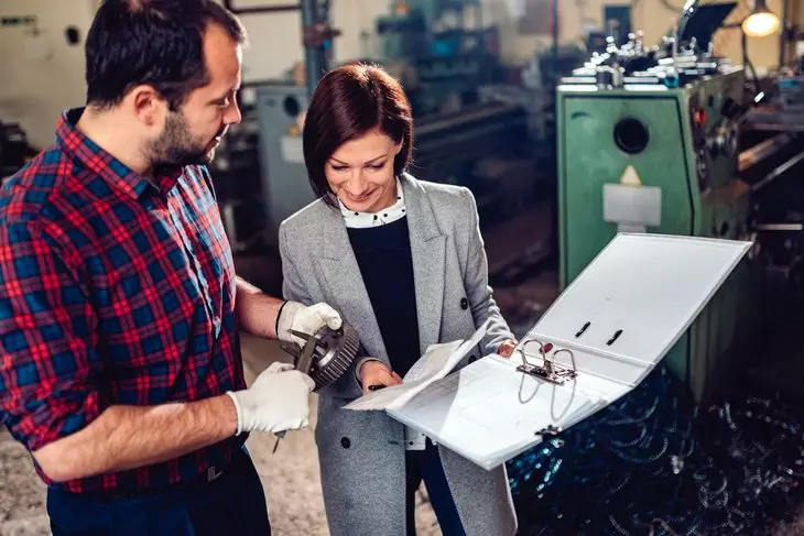 Maschinist mit Ingenieurin misst Zahnrad mit Messschieber in der industriellen Fertigungsfabrik