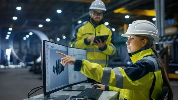 Industrie Weibliche Wirtschaftsingenieurin Frau Mann Fabrik Schutzhelm Designs Ingenieur spricht Tablet-Computer