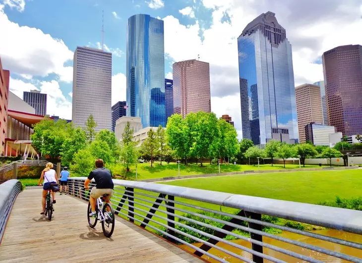 Ciclistas atravessam a ponte de madeira Buffalo Bayou Park vista do centro de Houston