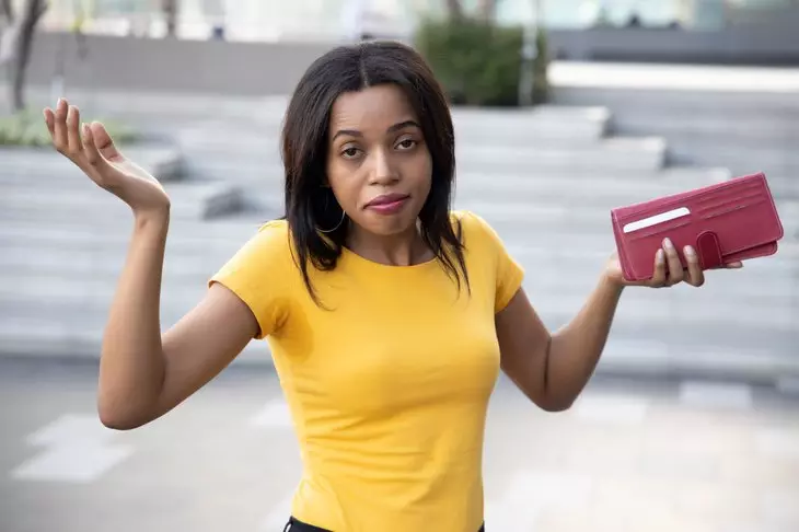 Mujer sosteniendo una billetera vacía