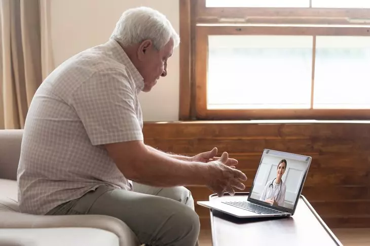 En eelere Mann schwätzt mat sengem Dokter op afstand op sengem Laptop