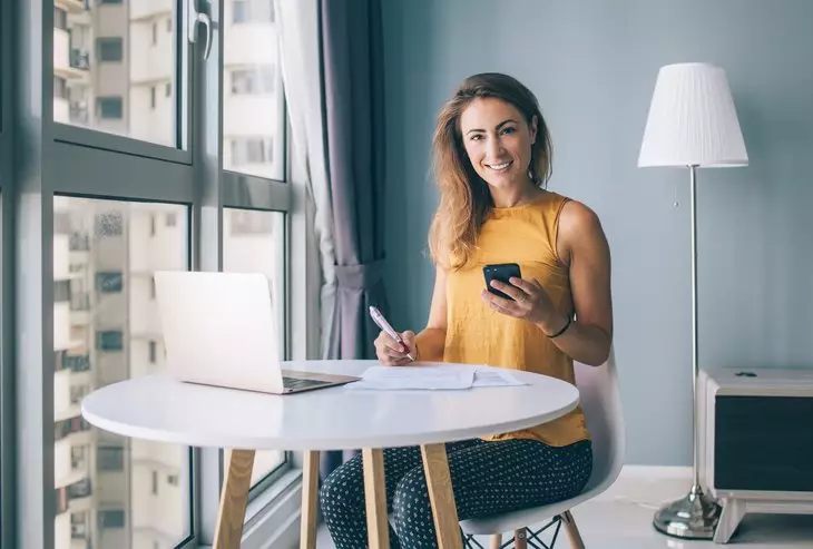 Vrou werk van die huis af op rekenaar en telefoon