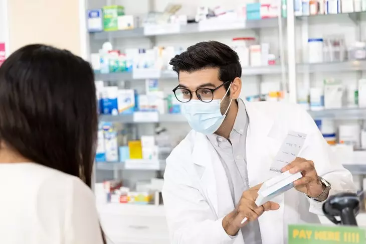 Farmacéutico explicando un medicamento recetado ao paciente na farmacia