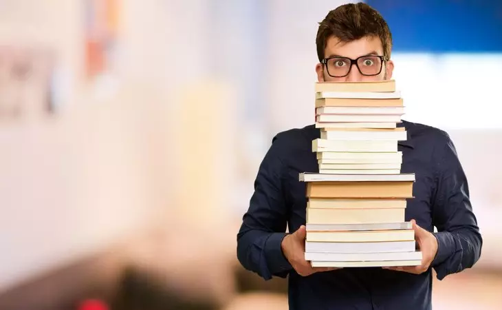 Giovane con una pila di libri.