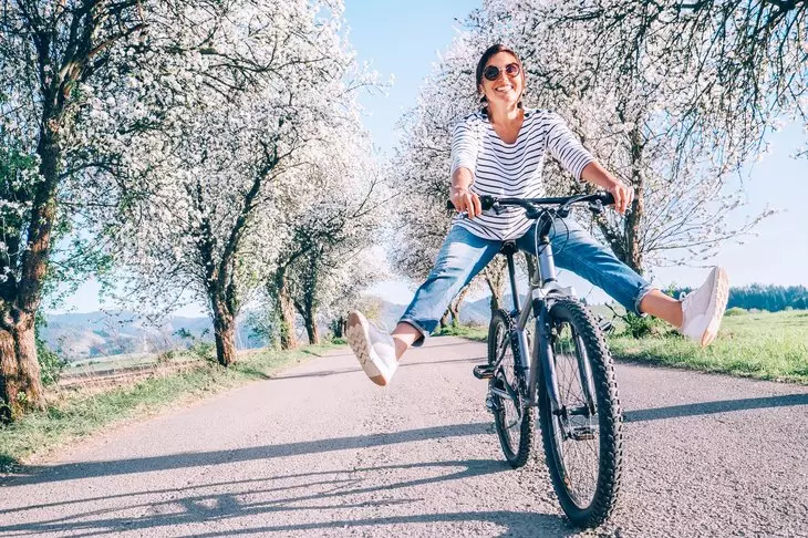 Dona feliç amb bicicleta a l'aire lliure a la primavera