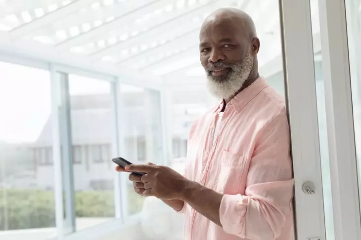 Een oudere zwarte man gebruikt een smartphone