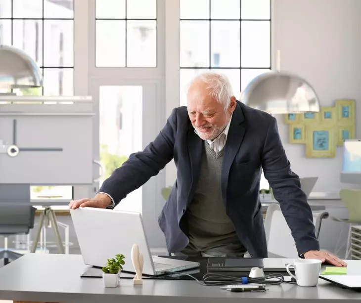 Un lavoratore anziano che controlla il suo computer portatile