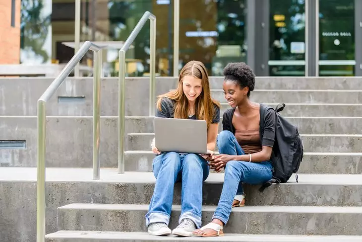 Kvindelige studerende ser på computeren på udendørs trapper.