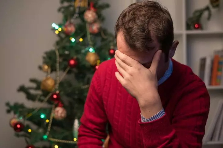 Hombre triste al lado de un árbol de navidad