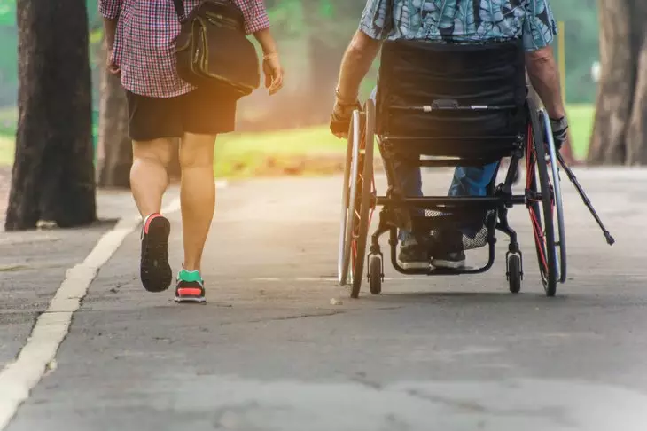 Pareja en un parque, uno caminando, otro en silla de ruedas