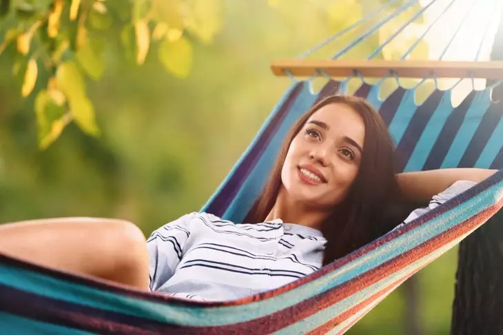 Muller feliz relaxándose nunha hamaca ao aire libre