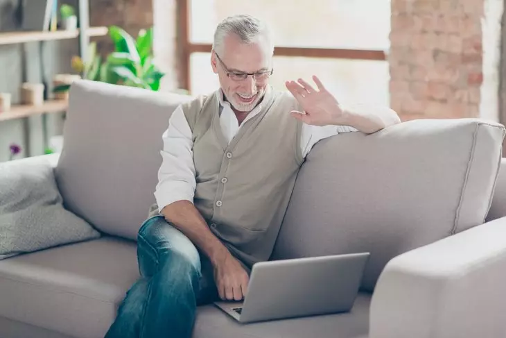 Ein Senior führt Video-Chats auf einem Laptop-Computer auf seinem Sofa im Wohnzimmer