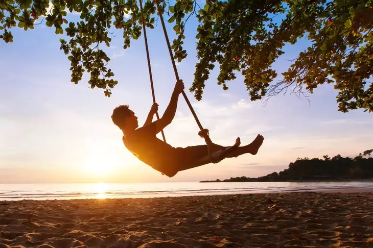 Un home balancea nunha praia ao pór do sol