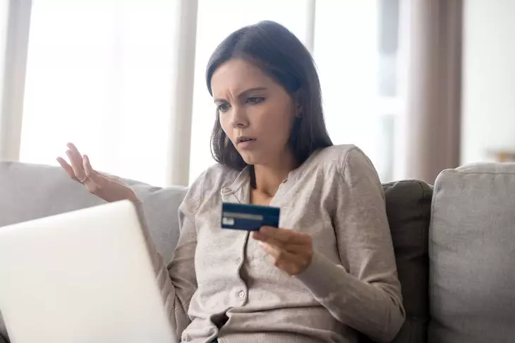 Frustrierte Frau mit Kreditkarte auf Laptop