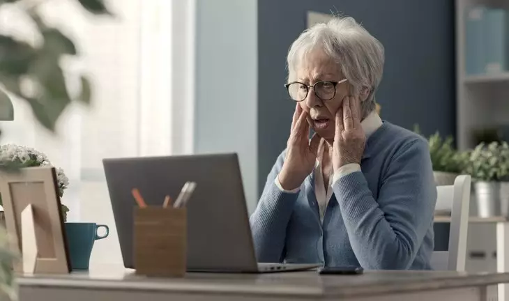 Sênior chateado surpreso enquanto em seu laptop