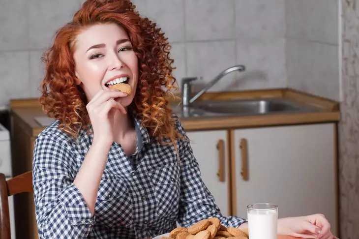 Frau isst Kekse mit Milch