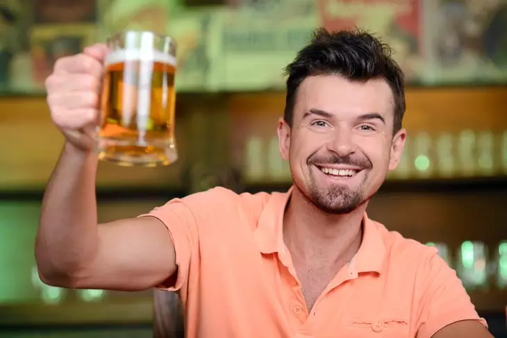 Homem levantando um copo de cerveja em alegria