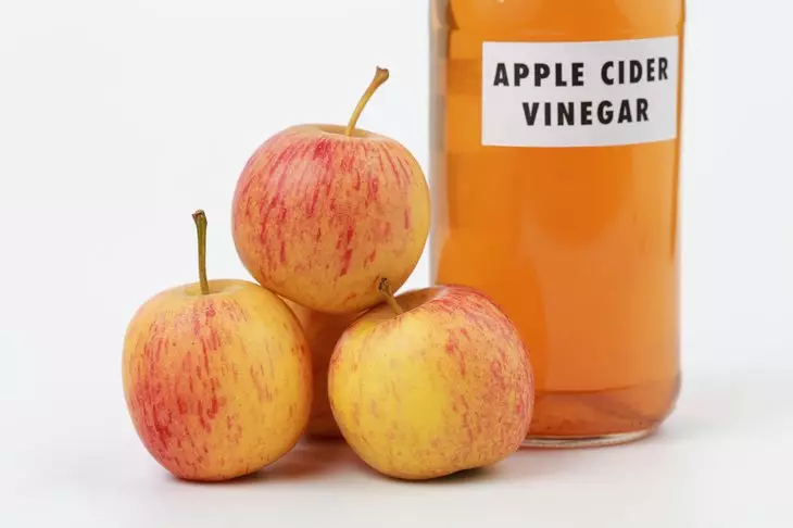 Vinagre de sidra de manzana junto a una pila de manzanas