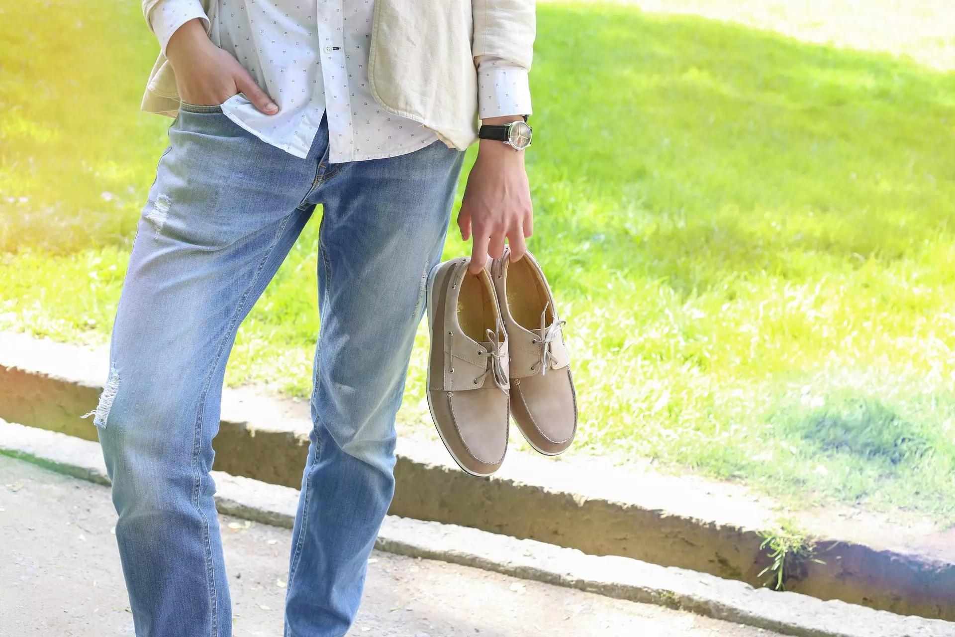 Étudiant marchant pieds nus dans le parc tenant des chaussures à la mode dans les mains.