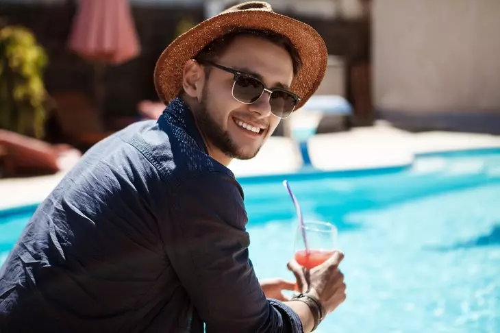 Homme à lunettes de soleil au bord de la piscine