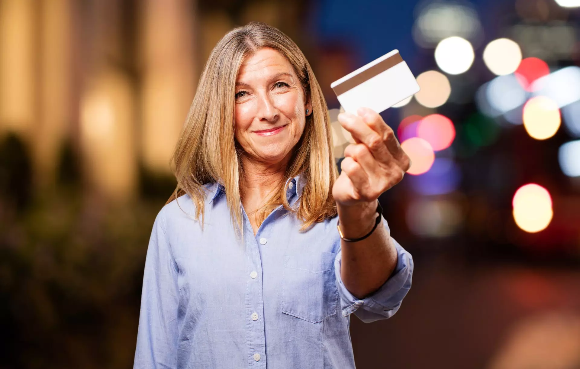 Een oudere vrouw houdt een creditcard omhoog